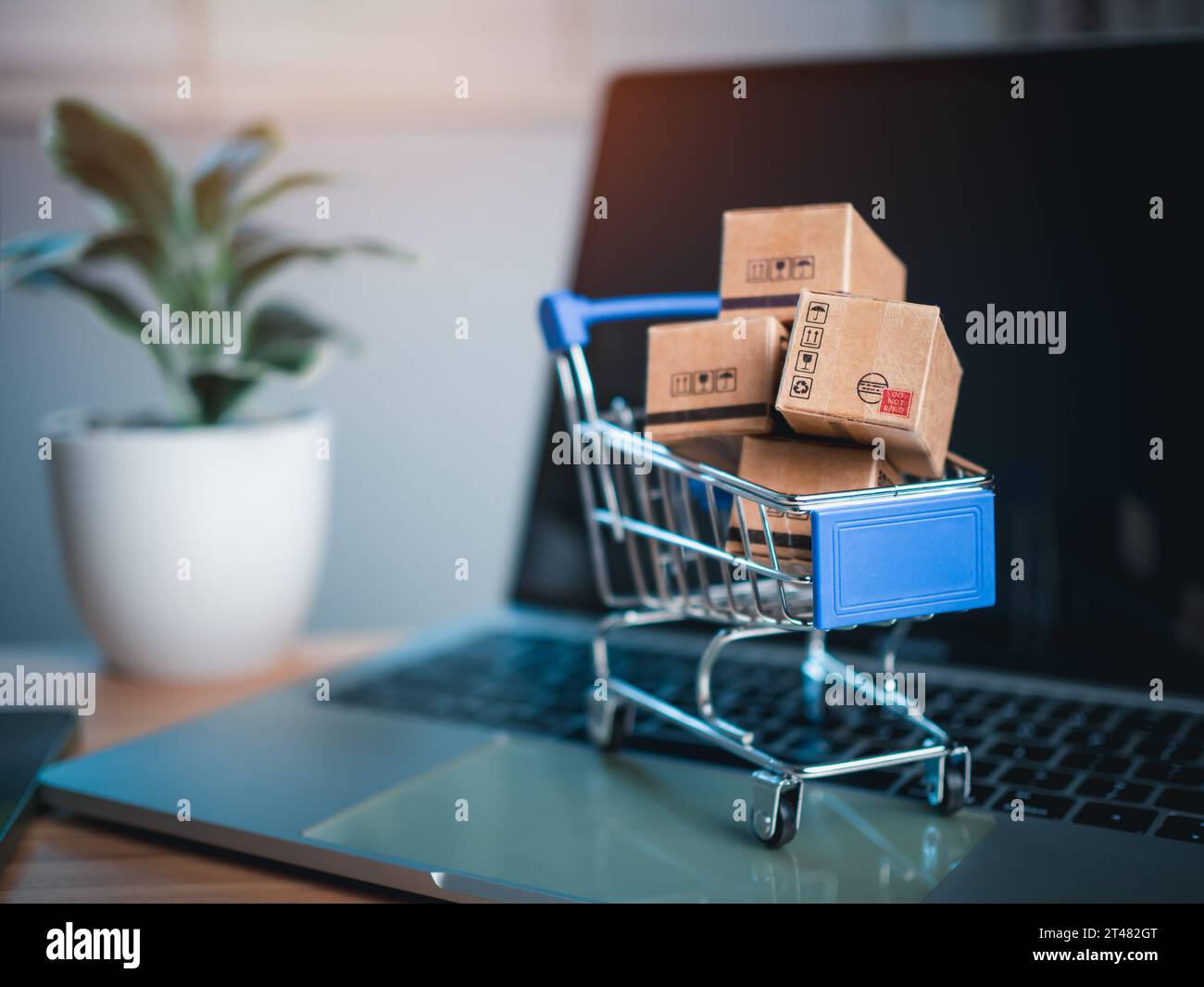 Shopping cart and product boxes placed on laptop computer represent ...
