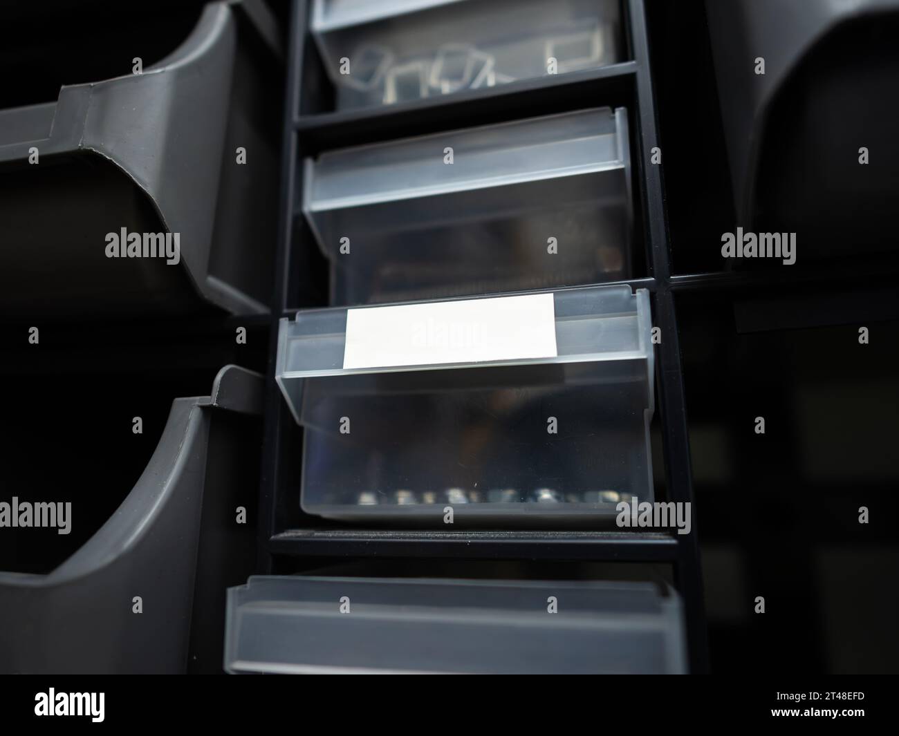 Storage box with an empty label in a garage workshop. Small parts are ...