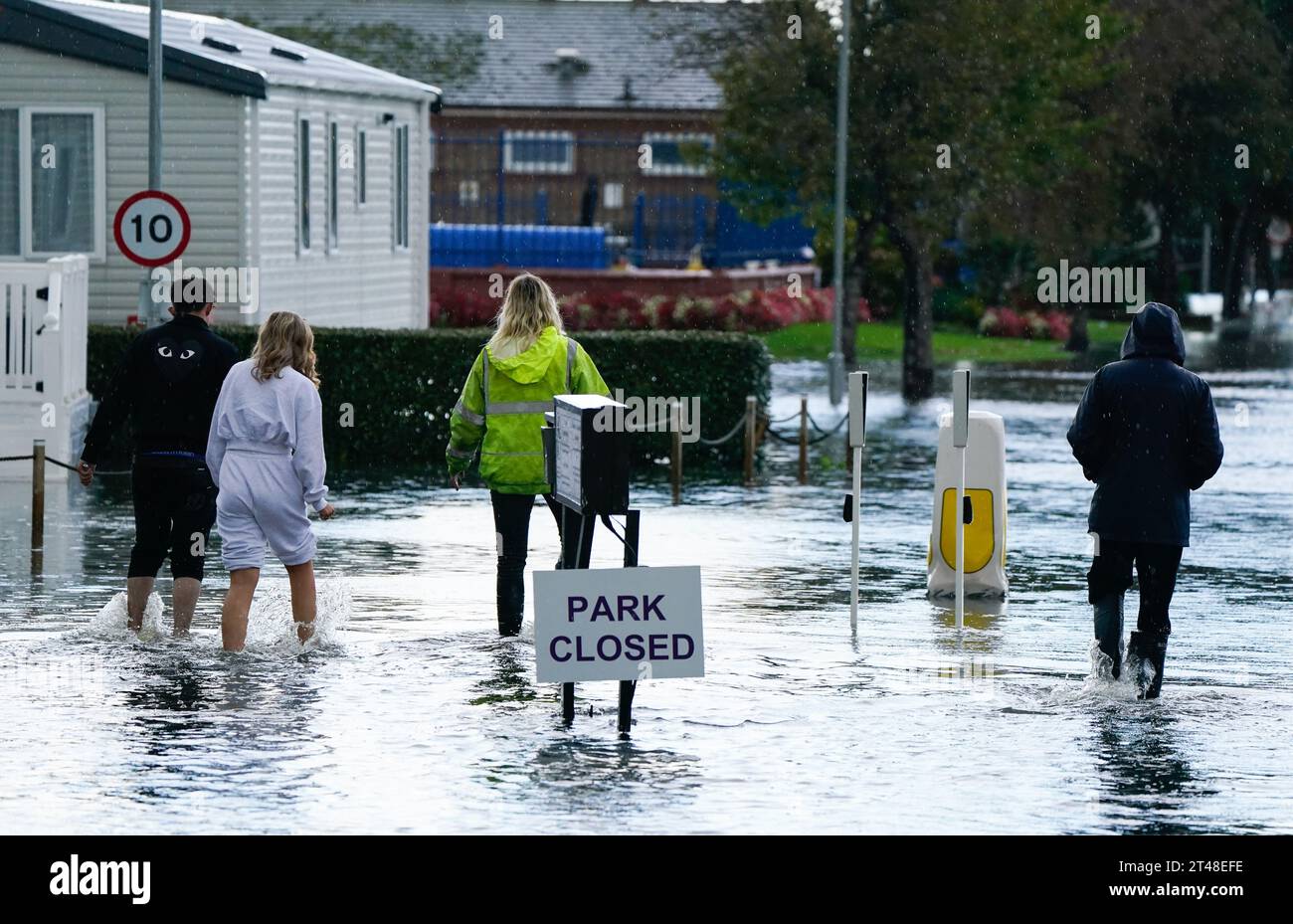 People walk through flood water as they make their way into the ...