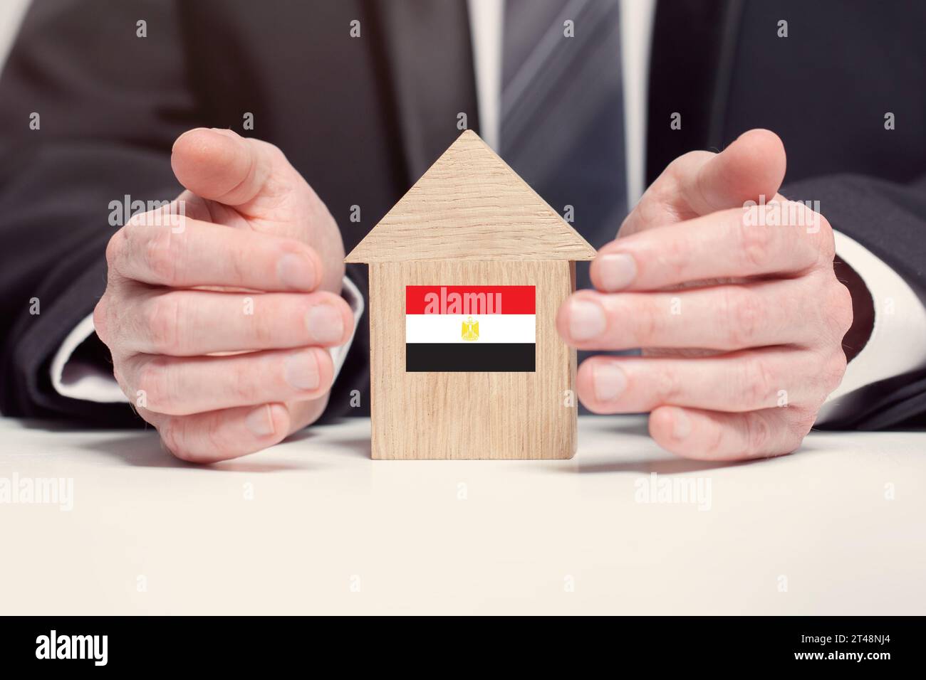 Businessman hand holding wooden home model with Egyptian union flag ...