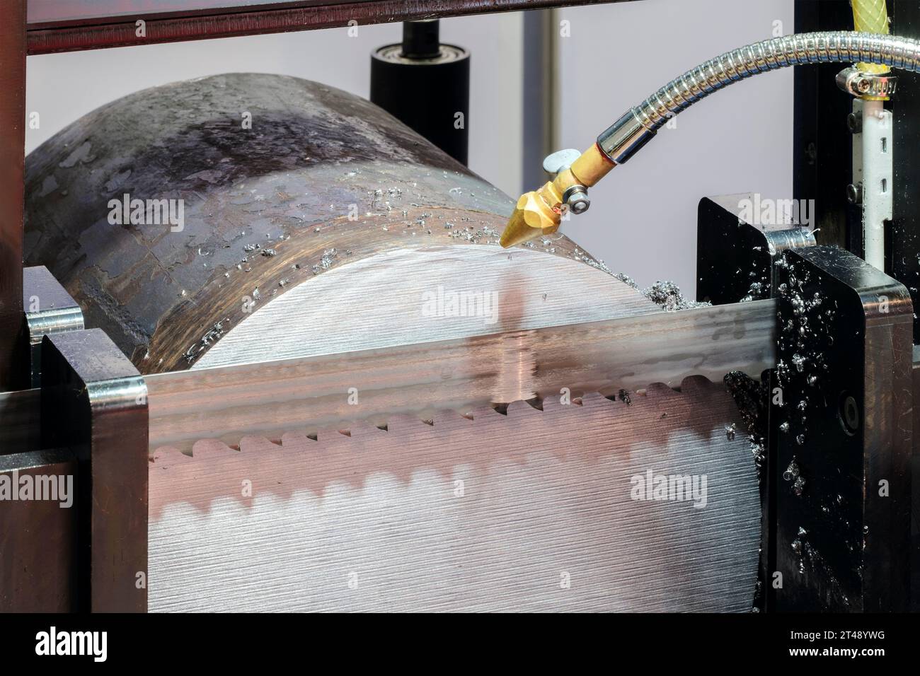 The automatic band saw machine cutting the metal bar with coolant method. The machine tool for ...