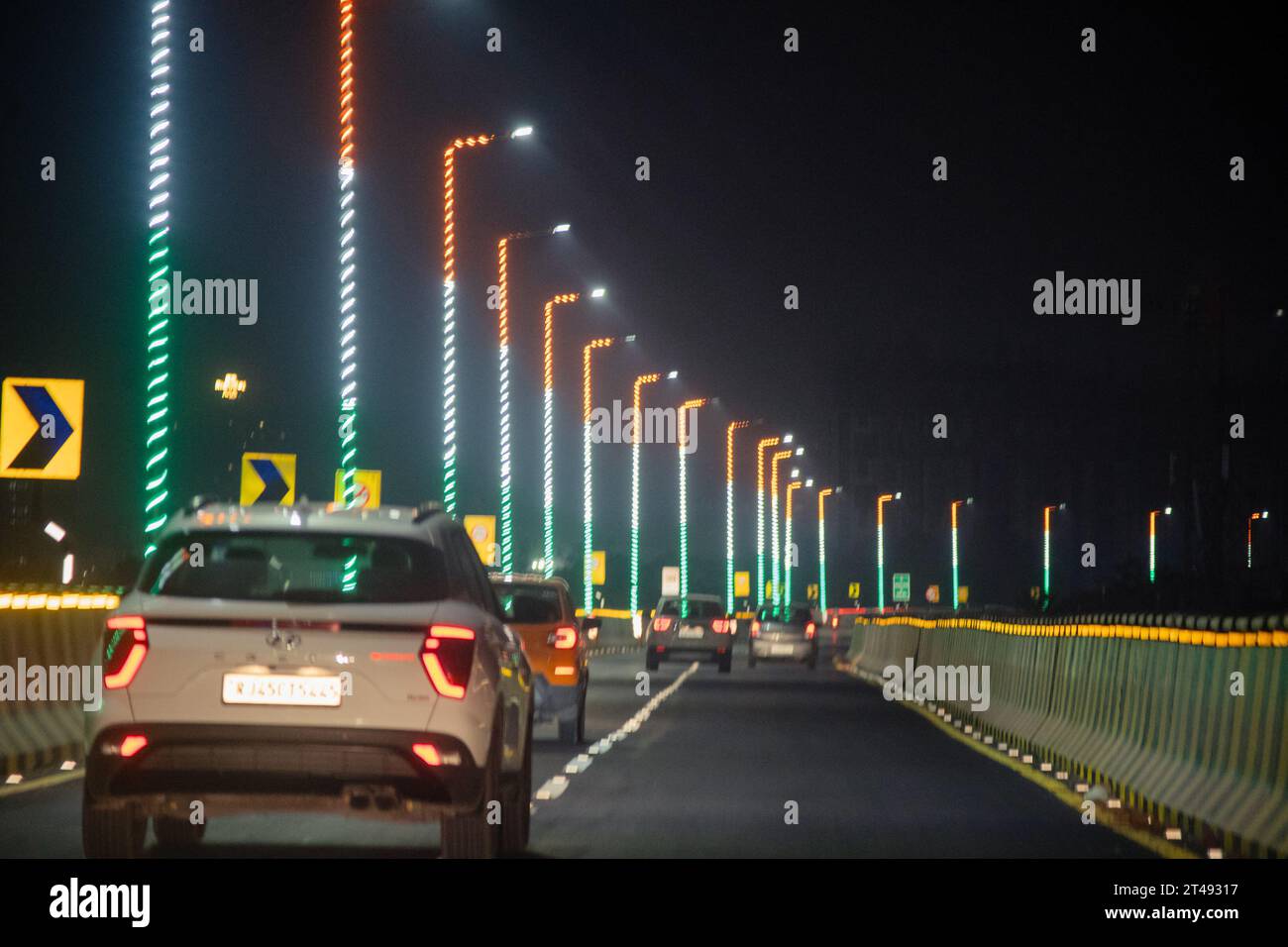 Cars moving between traffic lights covered in tri color lights with ...