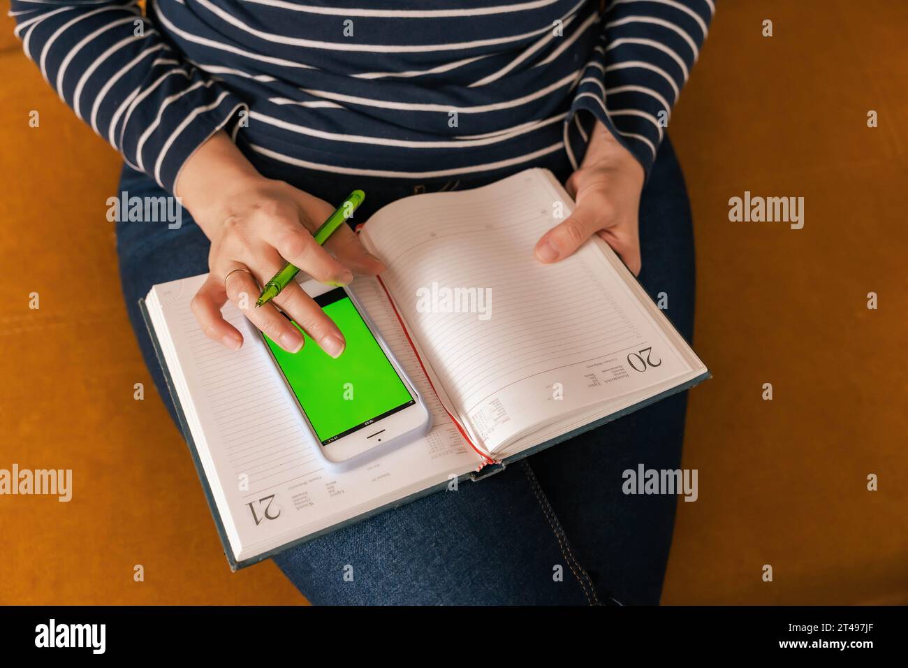 a woman makes notes in a notepad while working with a smartphone. She ...