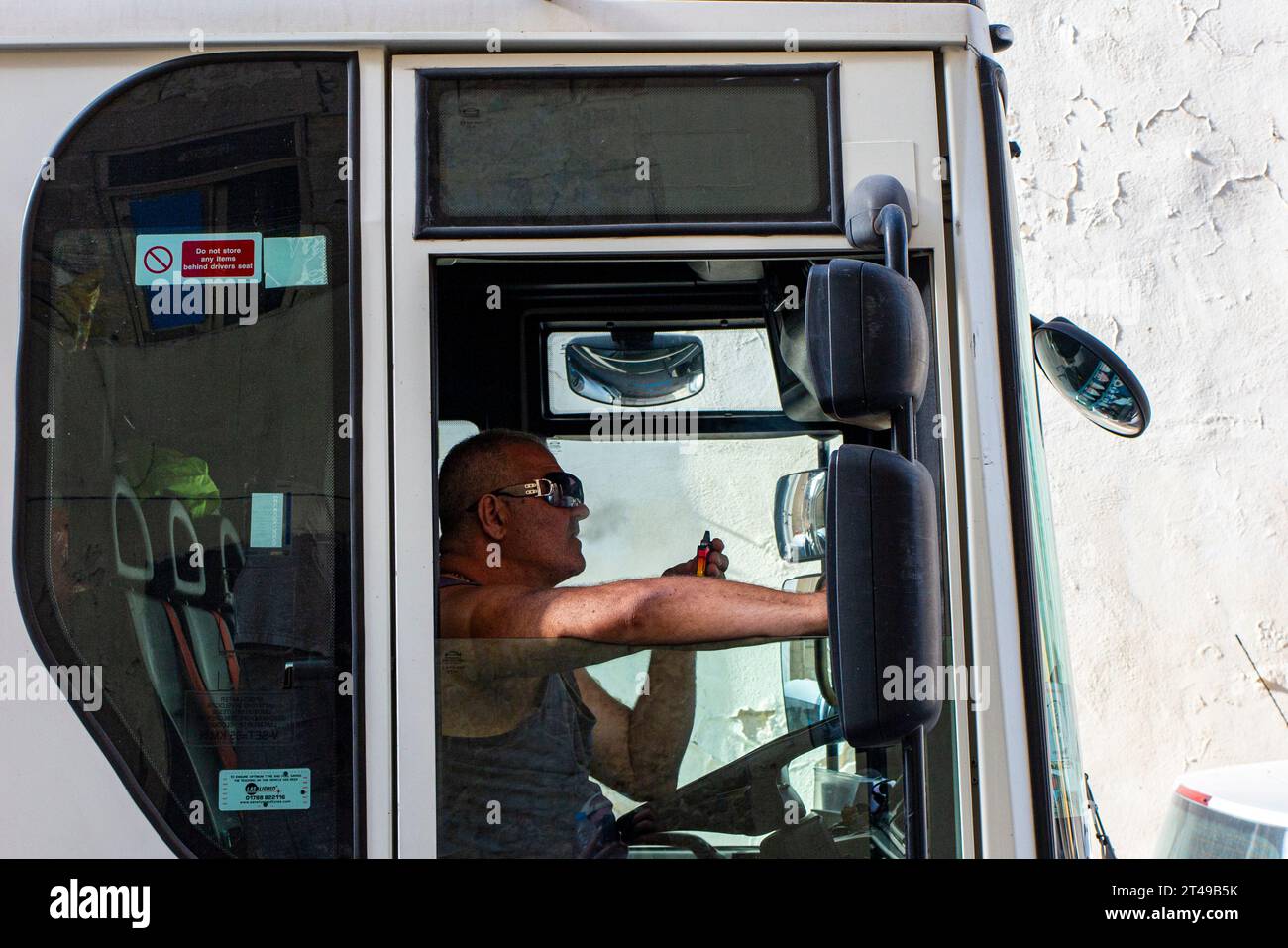 The driver of a refuse truck collecting rubbish enjoys a vape Stock ...