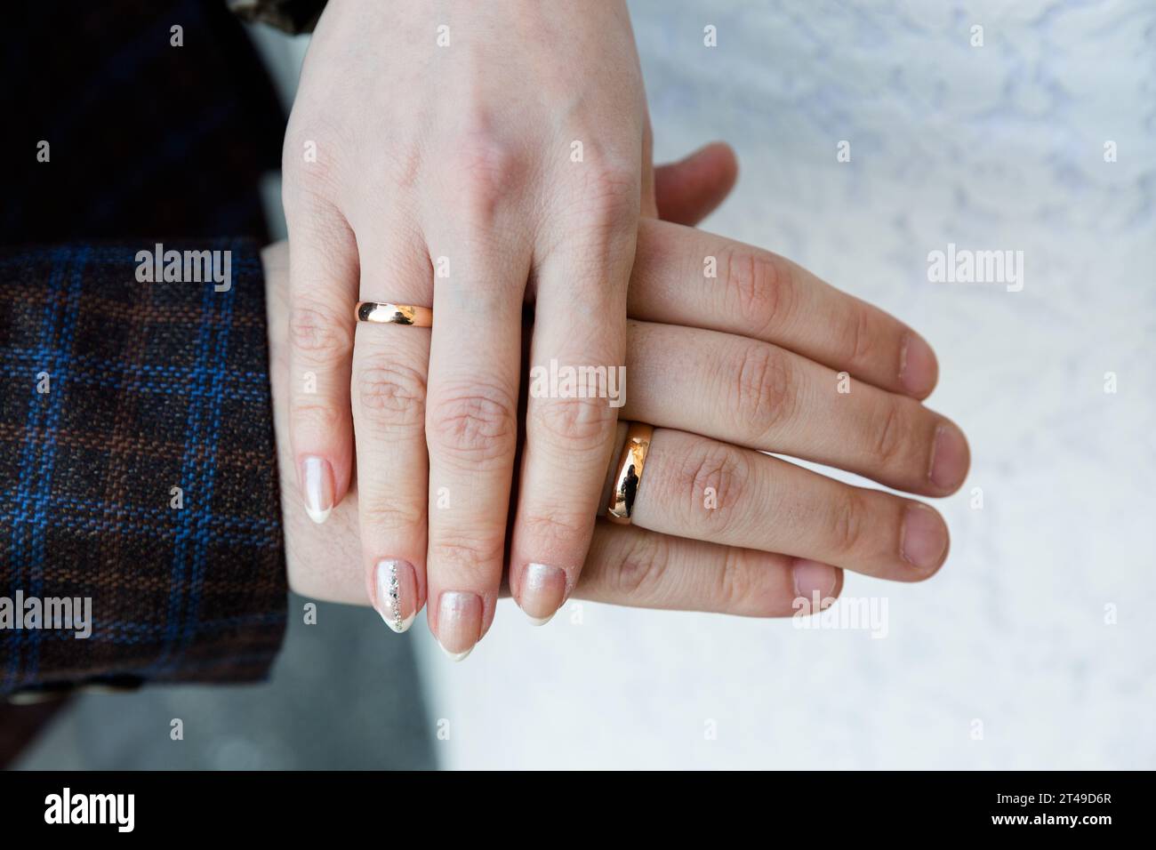 Interlaced hands with golden wedding rings. Focus on intricate ring ...