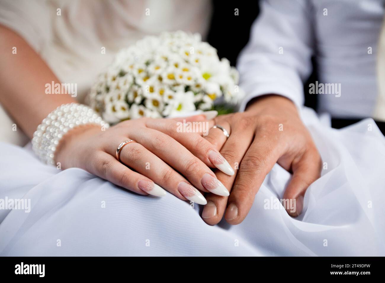 Close-up of bride and groom's hands intertwined, with a soft-focus ...