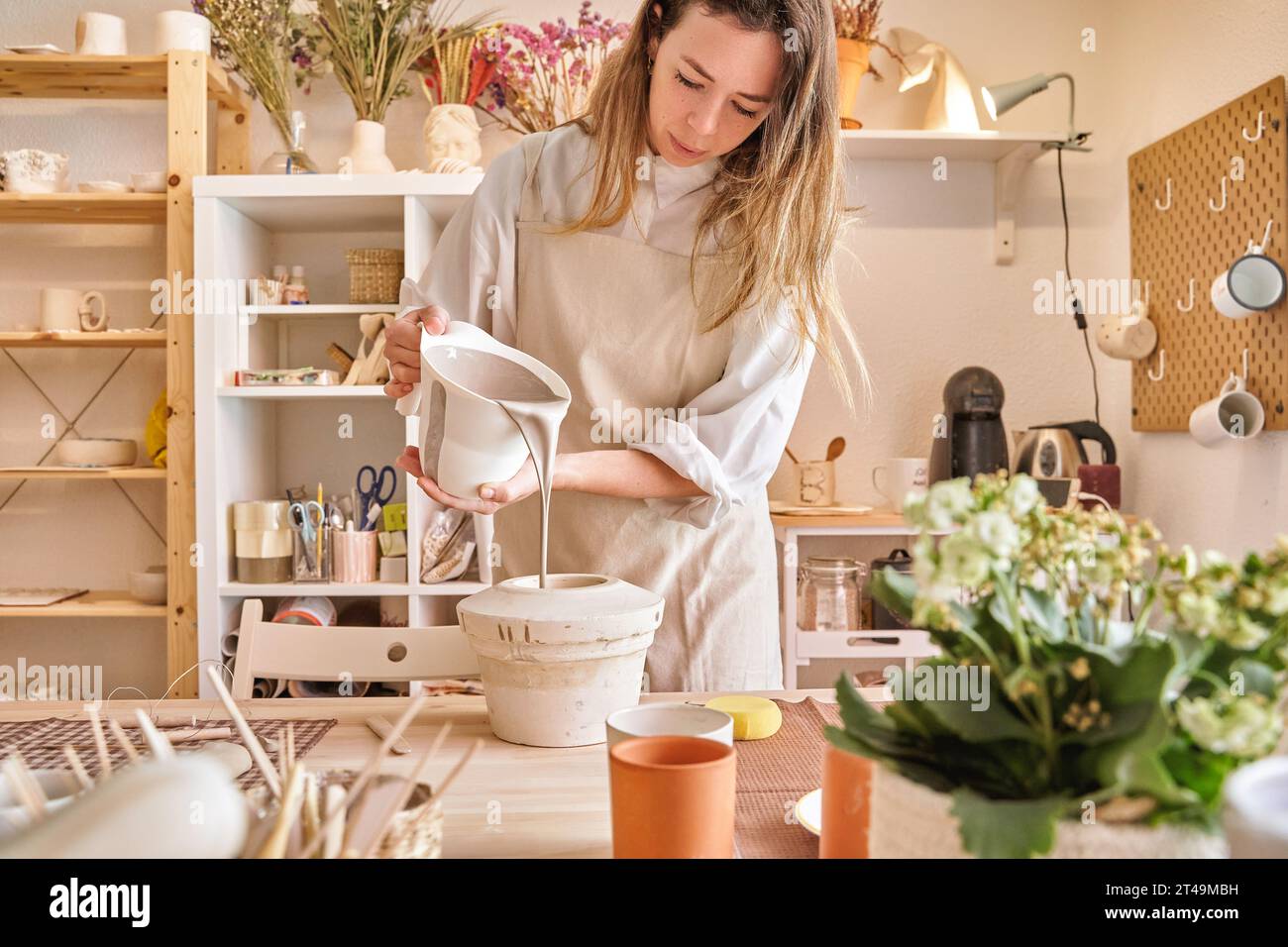 Craftswoman pouring clay into a mold to create a ceramic piece Stock ...