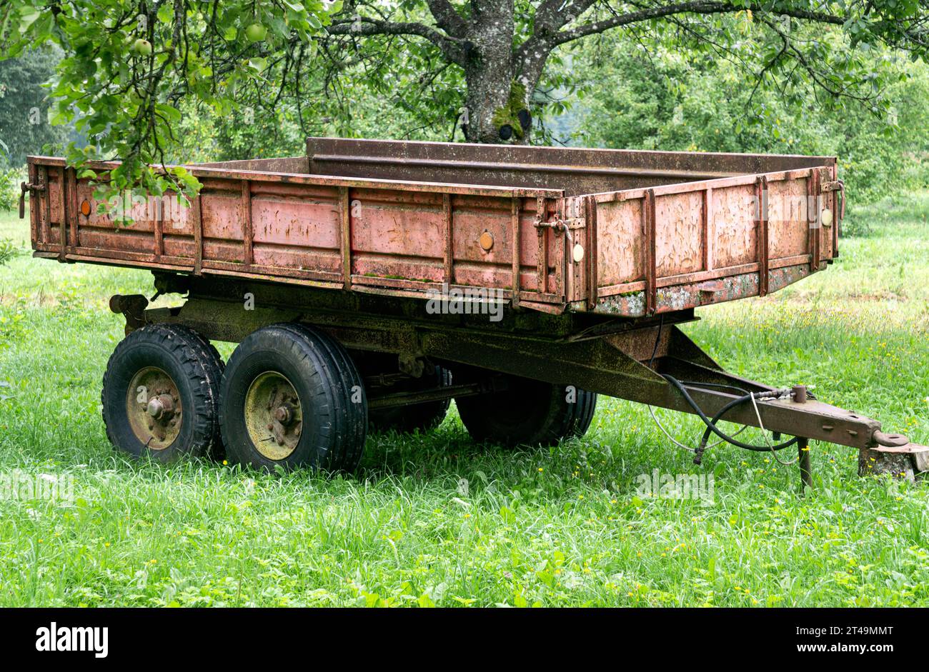 Old abandoned rusty tractor trailer. Standing on the grass under an ...