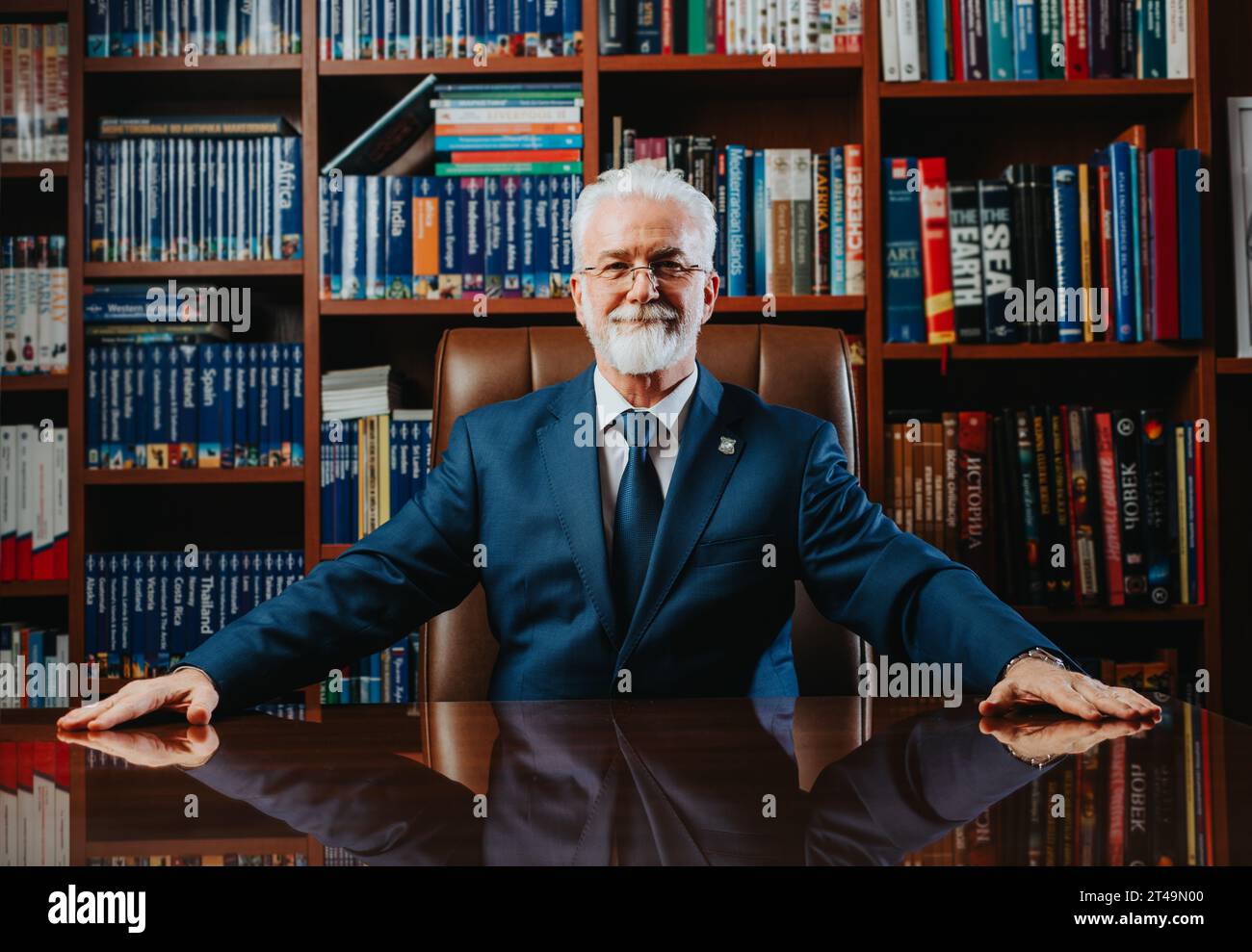 Experienced elderly rector poses confidently in a book-filled library ...