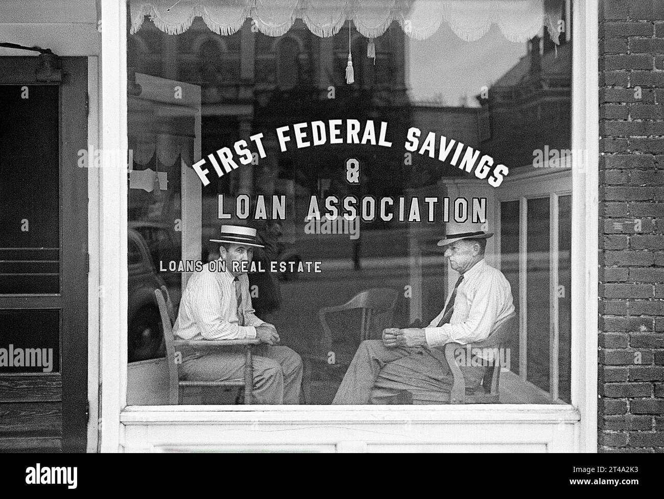 Two men sitting in window of First Federal Savings and Loan Association ...