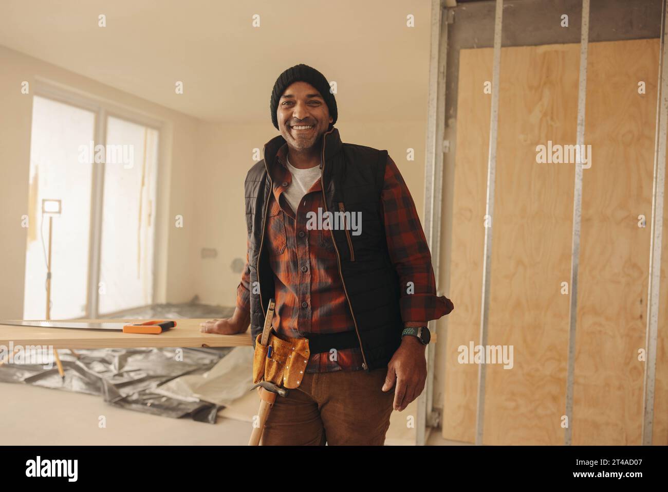 Happy DIY enthusiast wearing a tool belt and standing in a kitchen ...