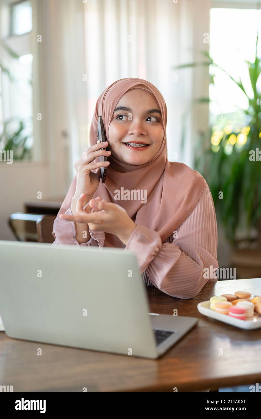 An attractive and cheerful young Asian-Muslim woman is calling someone ...