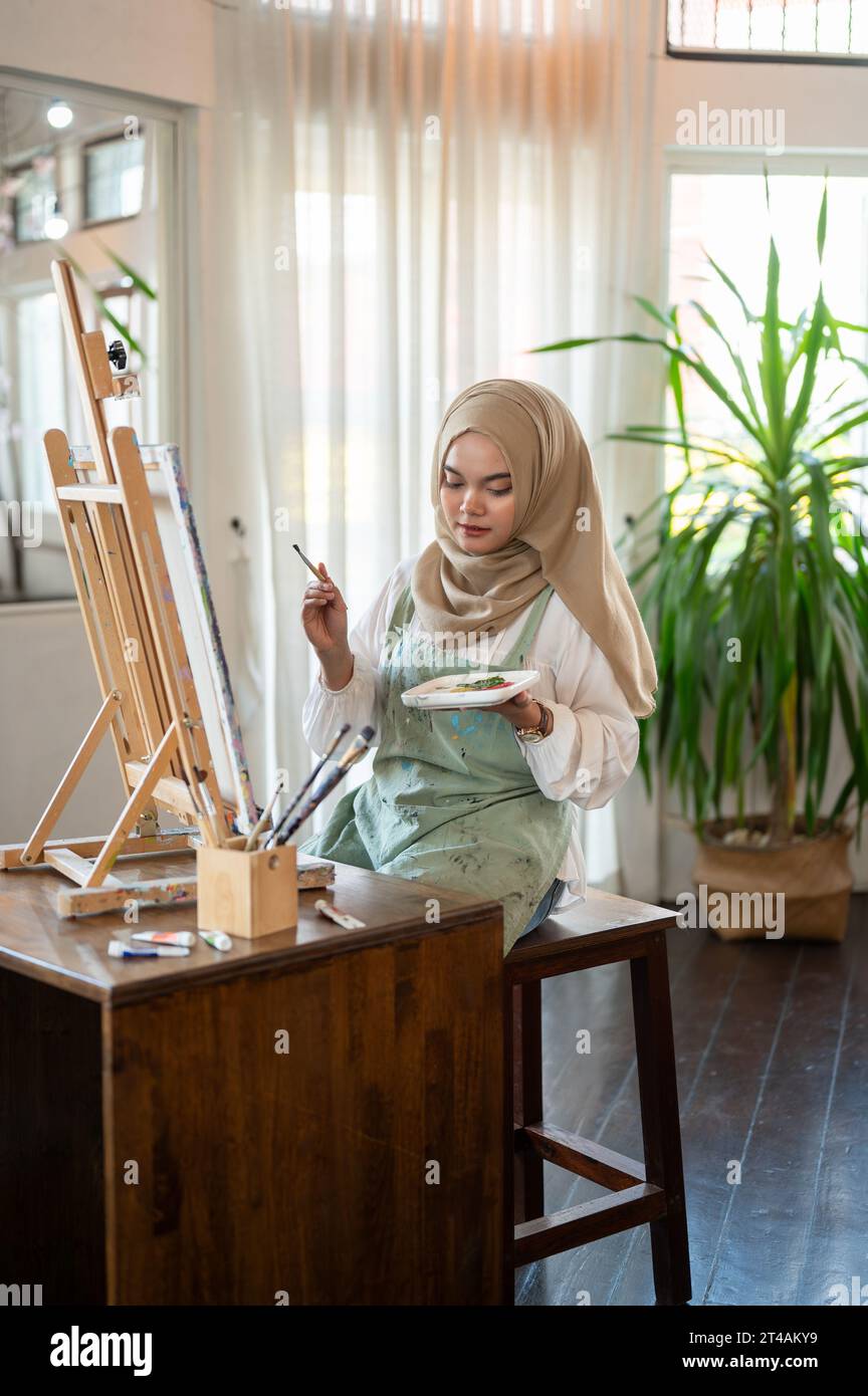 A creative and talented Asian-Muslim female artist in a hijab and apron ...