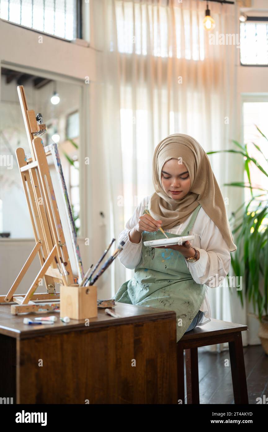 A creative and talented Asian-Muslim female artist in a hijab and apron ...