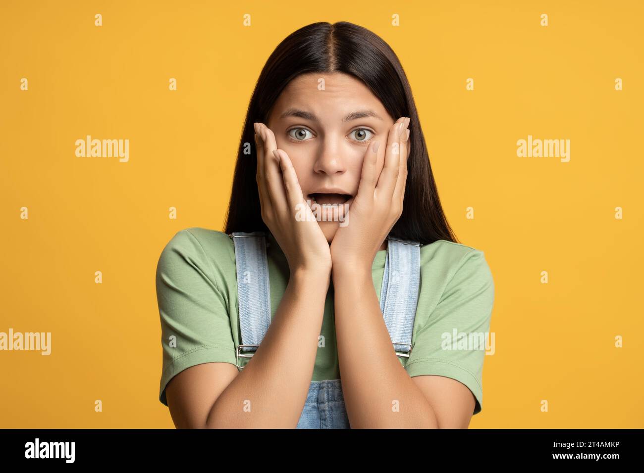 Portrait amazed shocked teenage girl looking at camera holding face ...