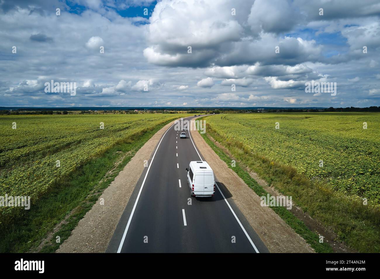 Aerial view of intercity road between green agricultural fields with ...