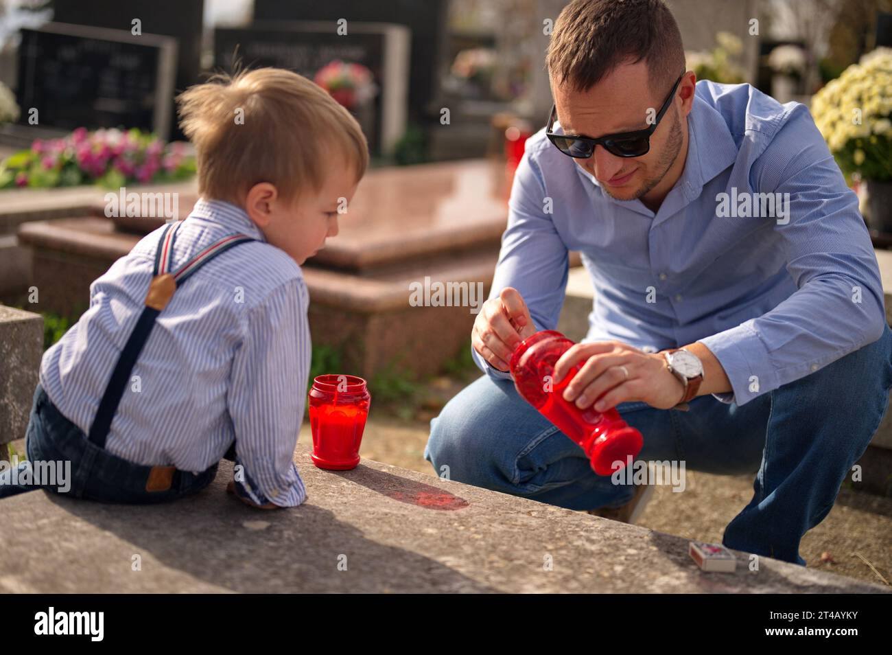Father and son lighting a candle at the grave Stock Photo - Alamy