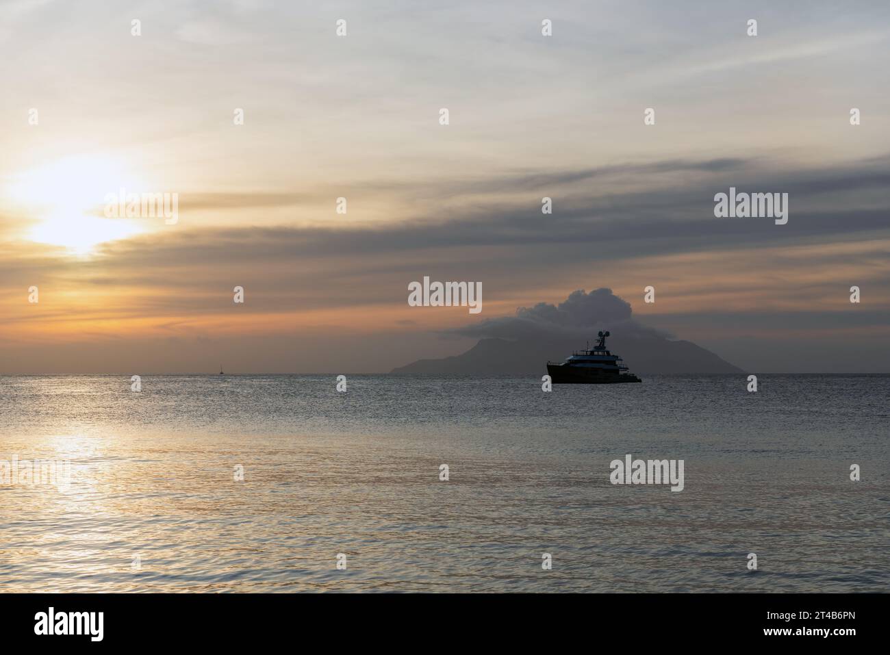 Ocean view with silhouette of a yacht under sunset sky. Mahe island ...
