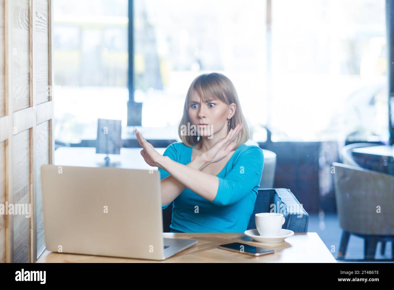 Portrait of strict serious young woman with blonde hair in blue shirt ...