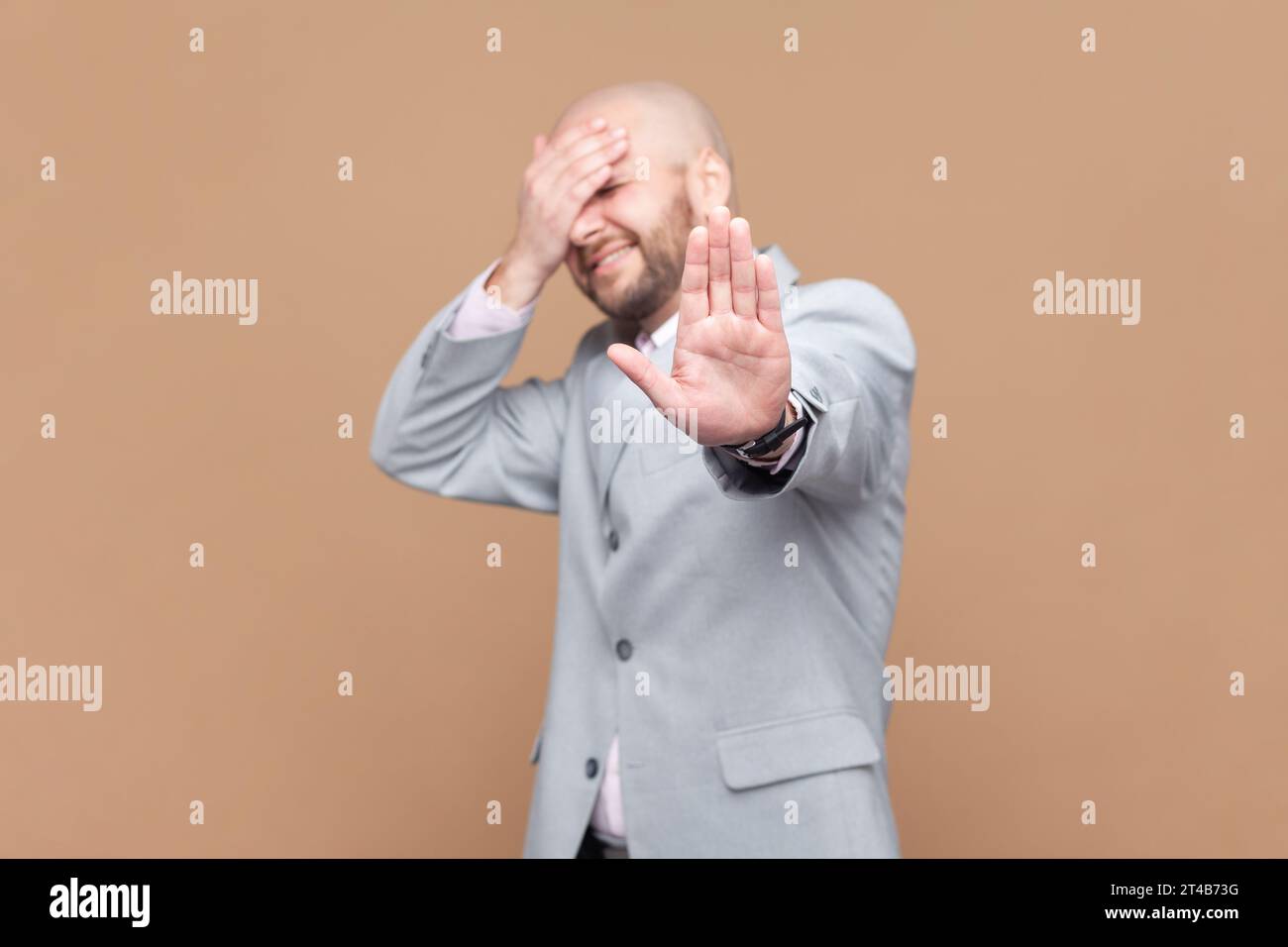 Portrait of scared frighten bald bearded man covering his face and ...