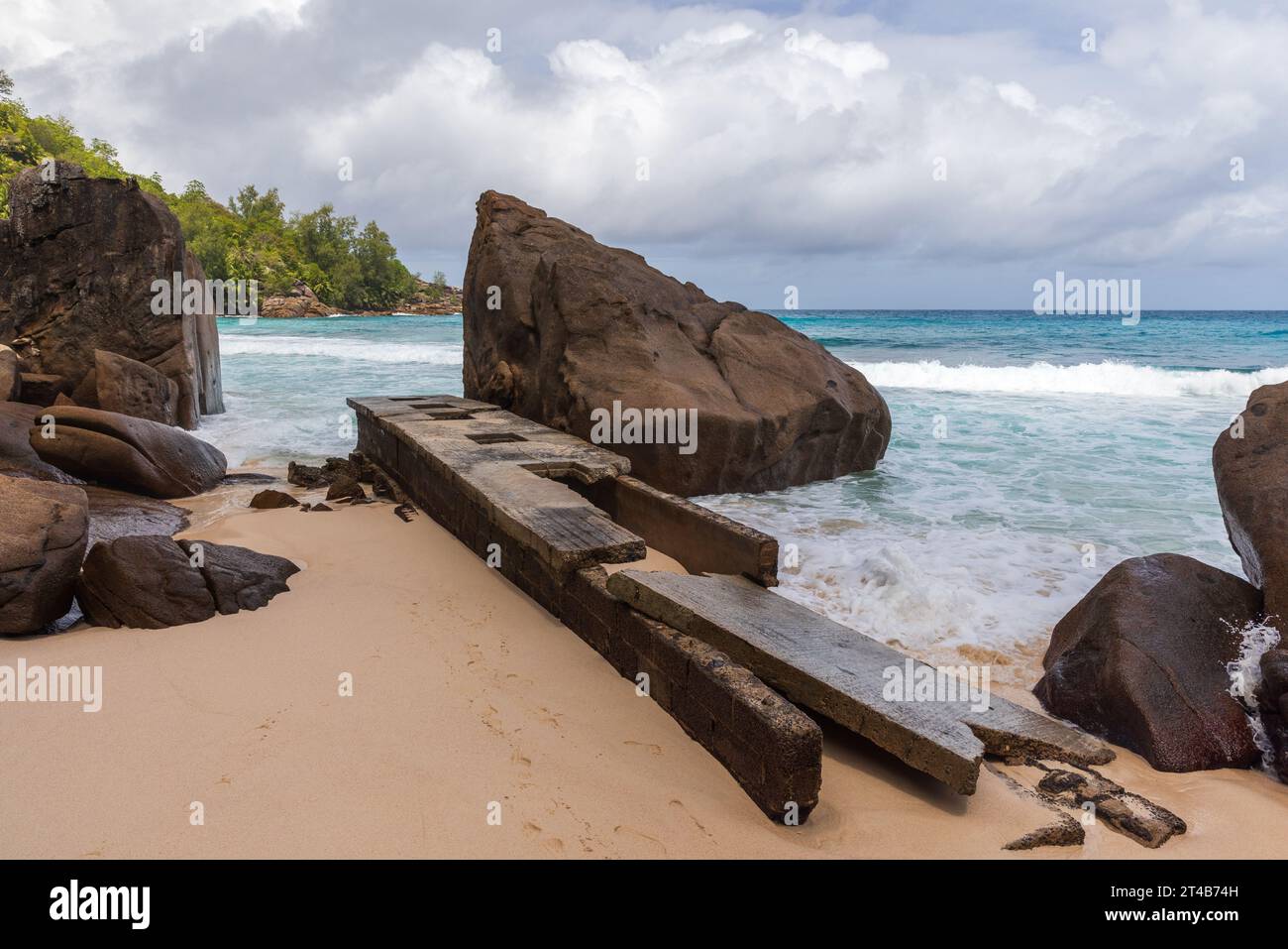 Coastal rocks and broken concrete pier at the coast of Anse Intendance ...