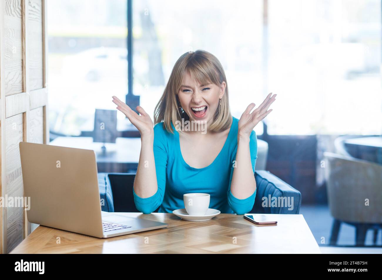 Portrait of sad tired angry young woman with blonde hair in blue shirt ...