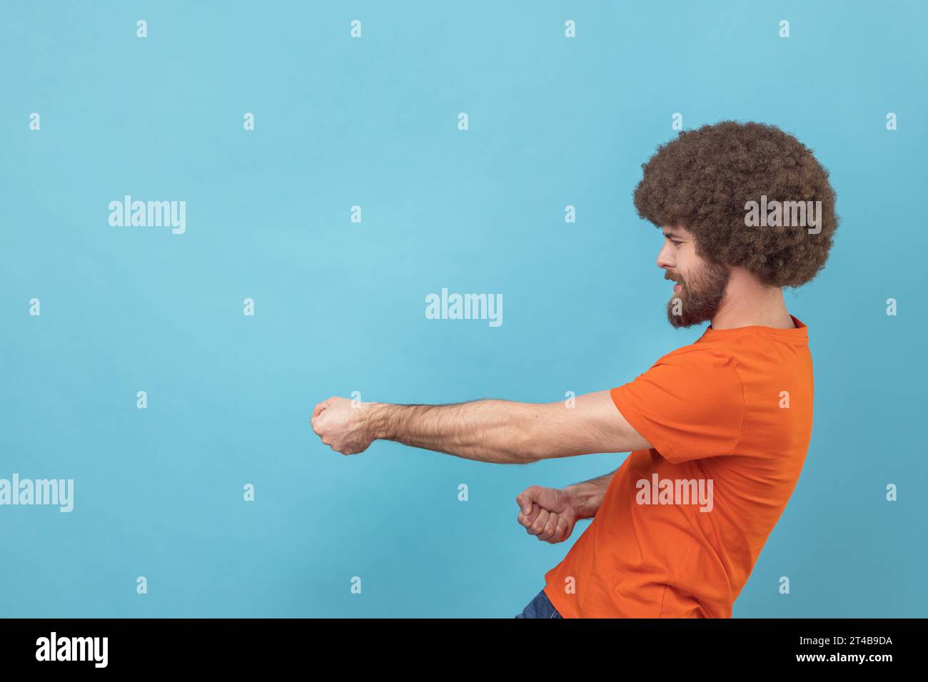 Side view of purposeful man with Afro hairstyle wearing orange T-shirt ...