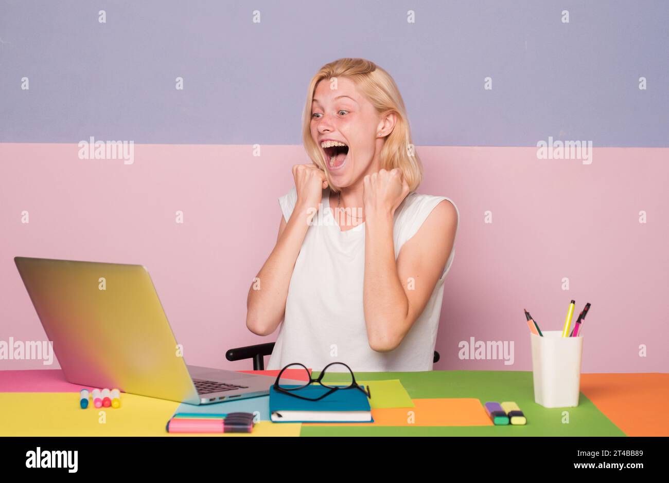 Female excited teacher use laptop at her desk marking students work ...