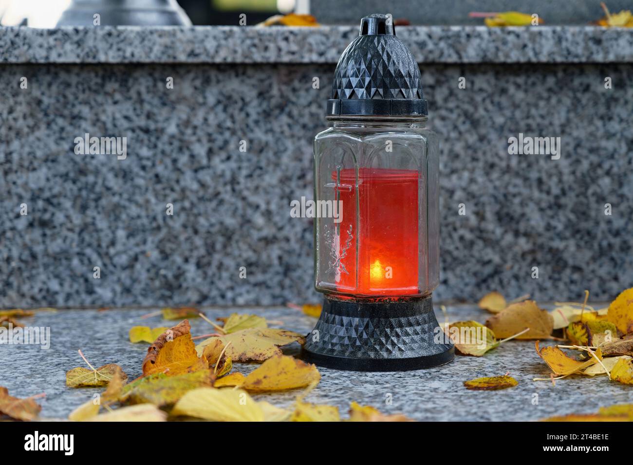 All Souls' Day. A lit candle on the grave. Background with cemetery ...