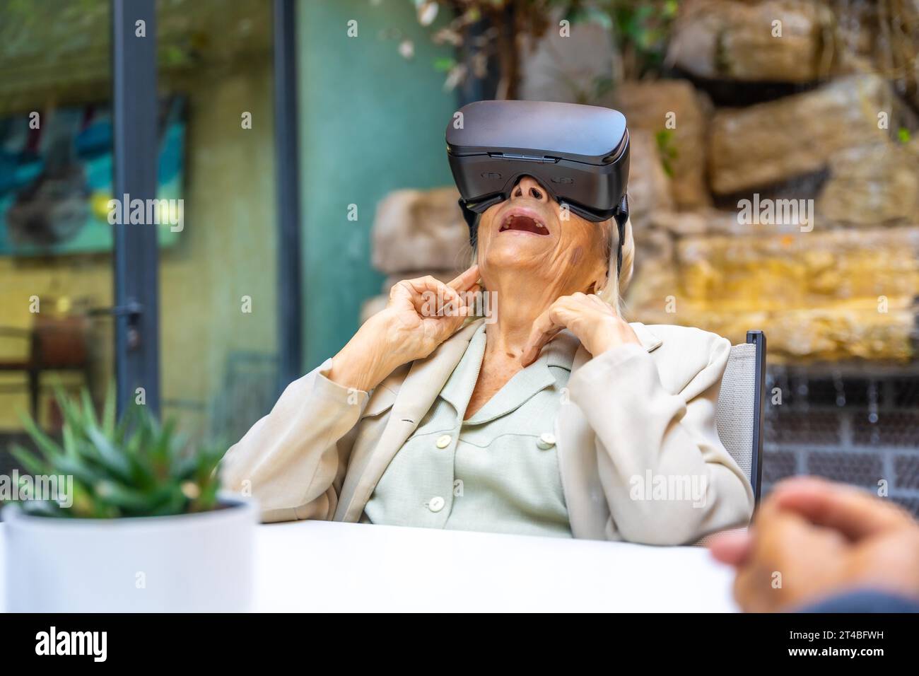 Elder woman looking up while using Virtual reality goggles sitting on a ...