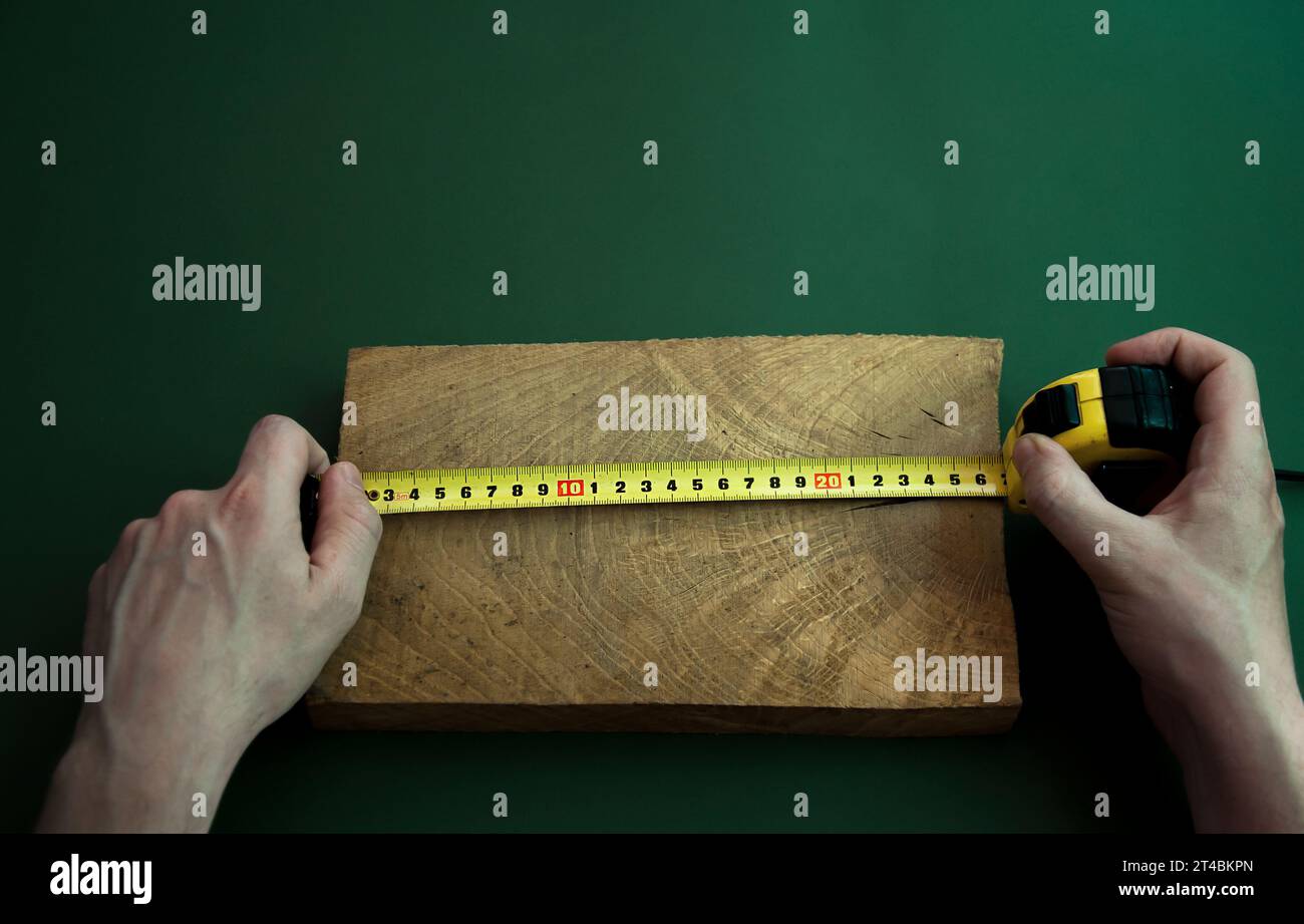 Measuring wooden board with measuring roulette. Yellow measure tape is ...