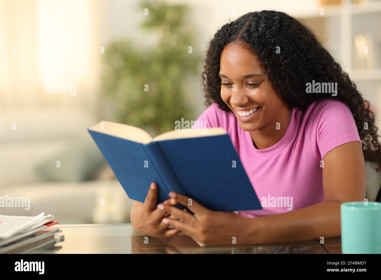 Happy black woman reading a paper book sitting at home Stock Photo - Alamy