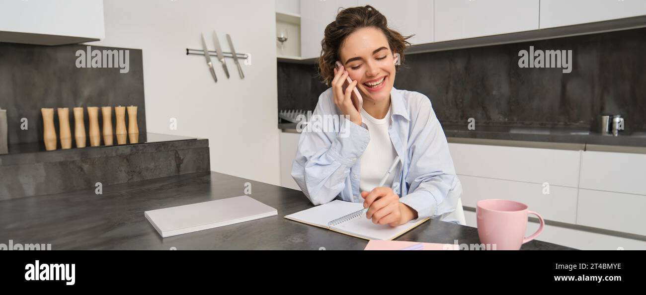 Image of woman working from home, writing down information during a ...