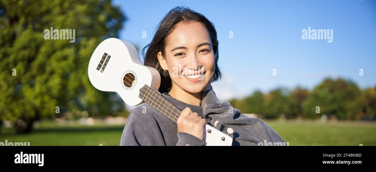 Portrait of beautiful smiling girl with ukulele, asian woman with ...