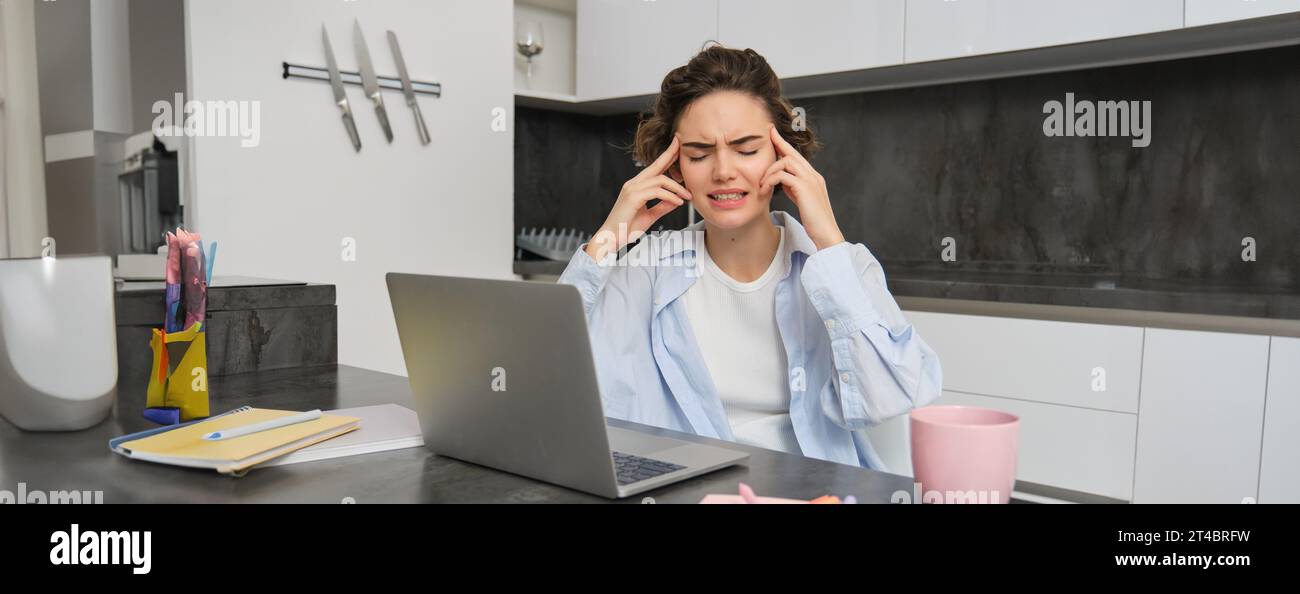 Portrait of troubled young woman, sits near laptop with frustrated face ...