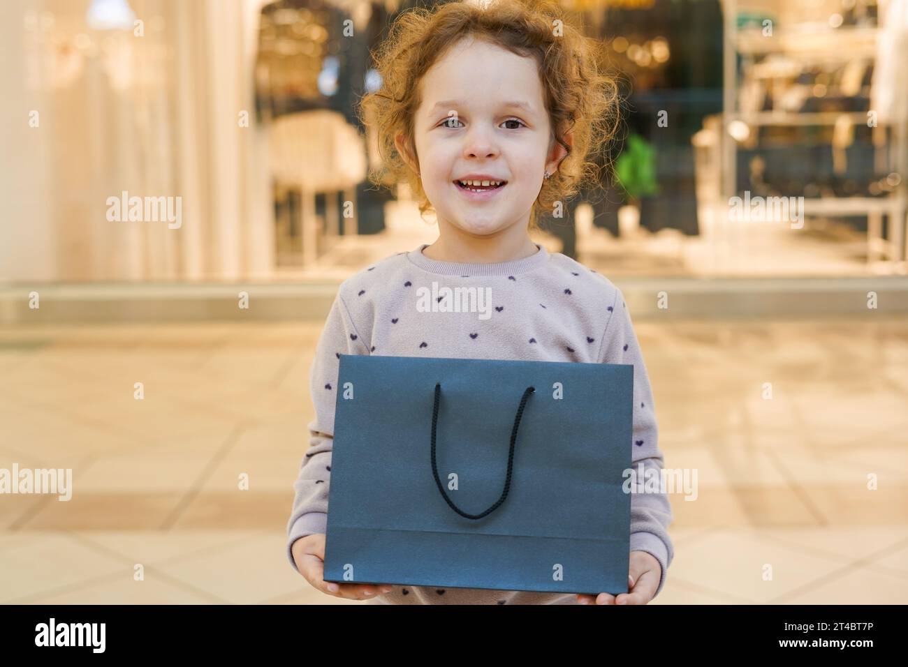 Cute child girl with curly hair holding black with shopping bag in ...