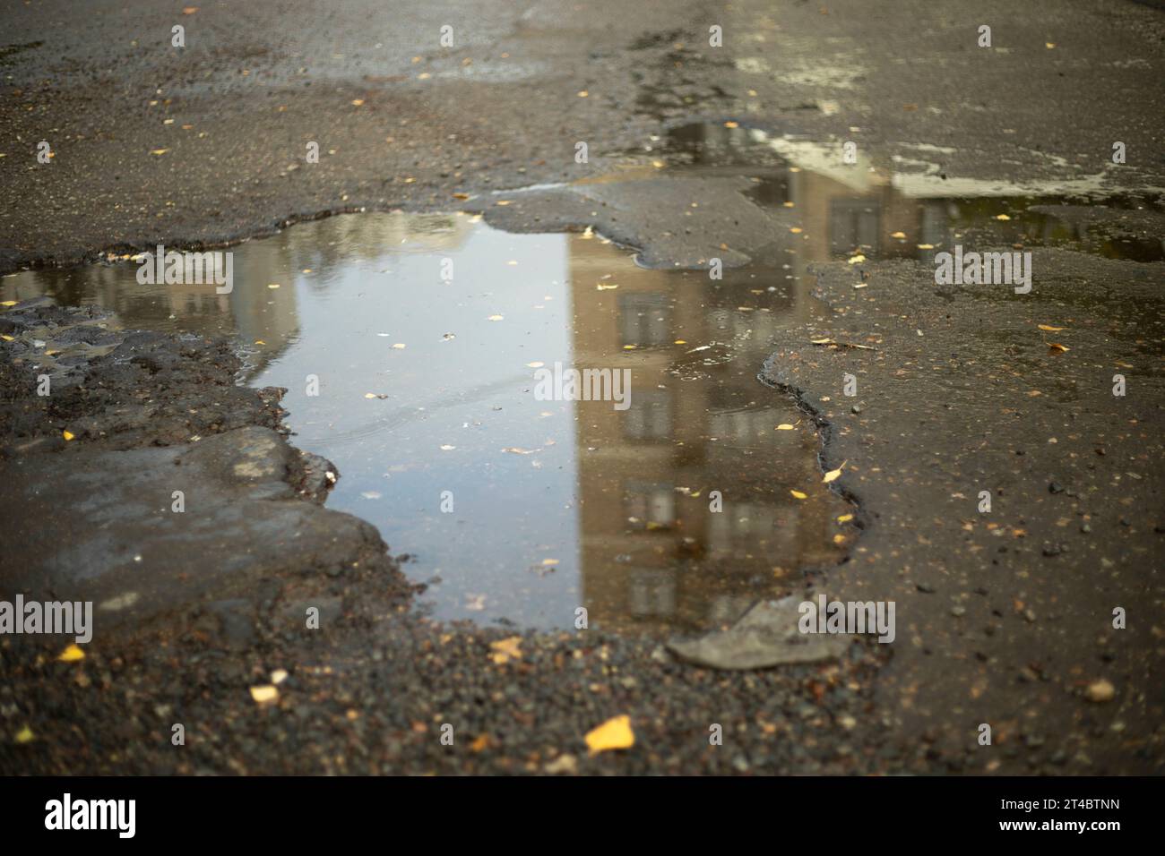 The puddle on the pavement. Wet road. Asphalt parts. Pit on the road ...
