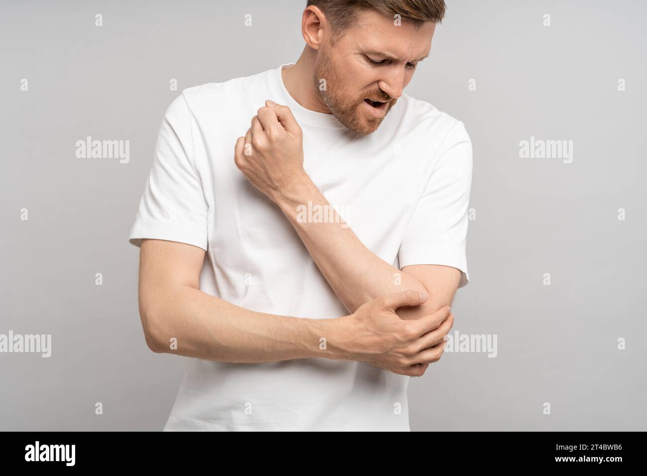 Middle aged man touching hand elbow feeling pain isolated on gray ...