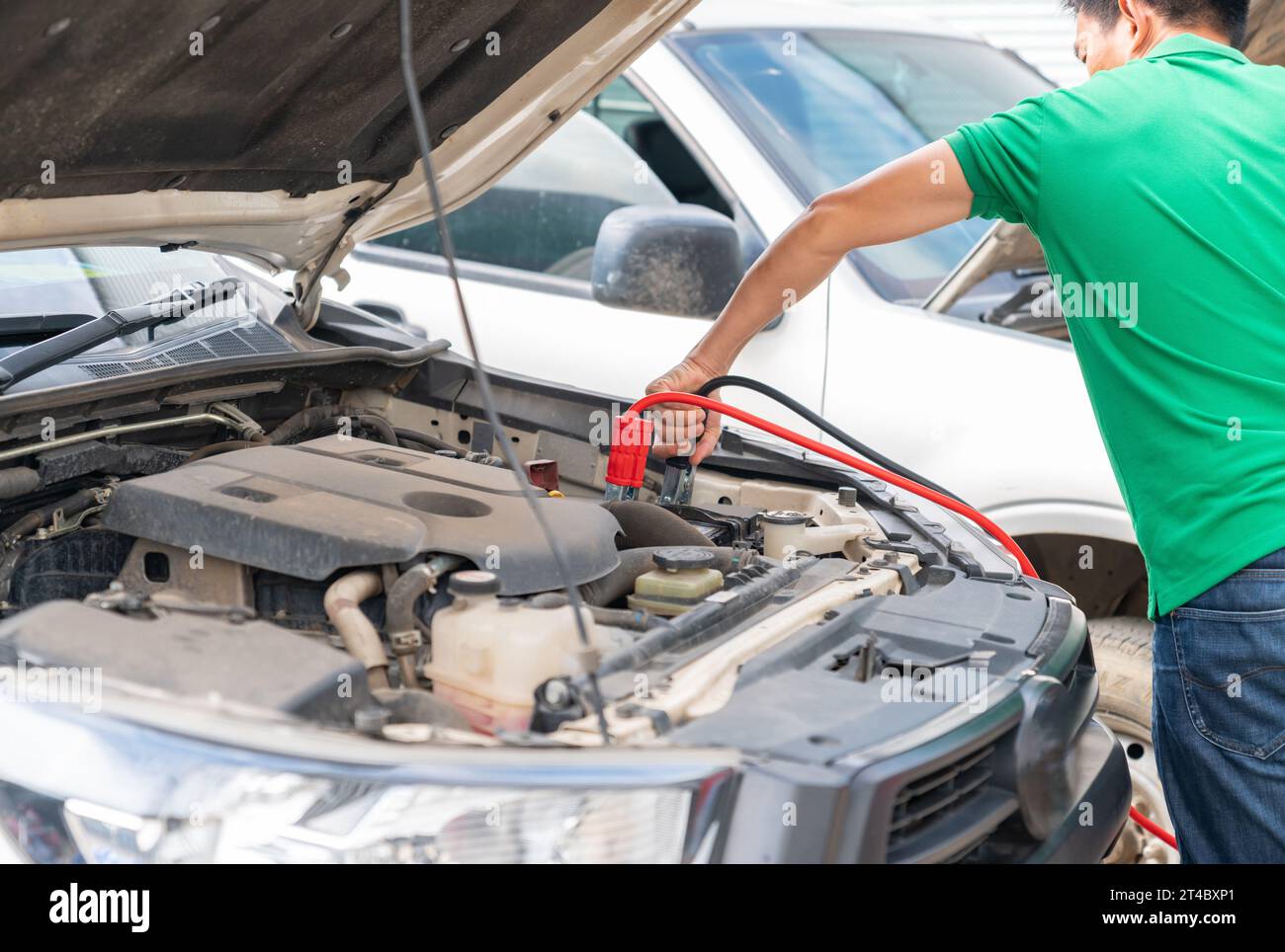 Technician Charging car battery with electricity trough jumper cables ...