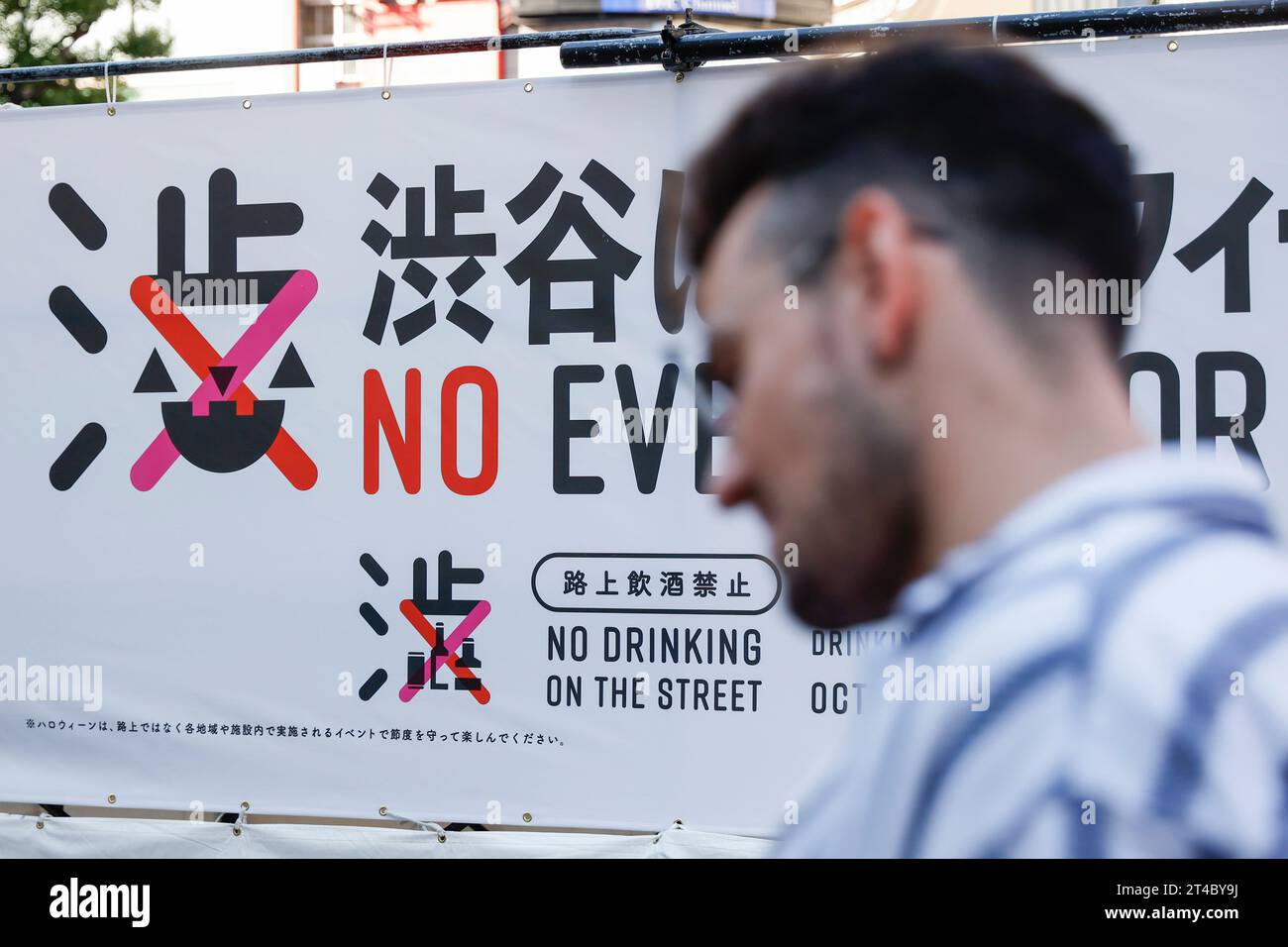 Tokyo, Japan. 30th Oct, 2023. A man walks past a signboard prohibiting ...