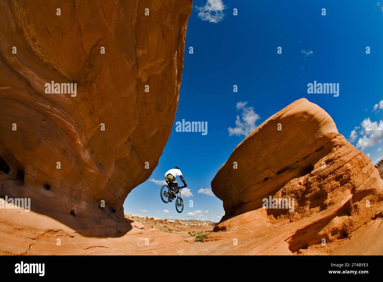 Mountain biker jumping off rock cliff in the Bartlett Wash area, Moab ...