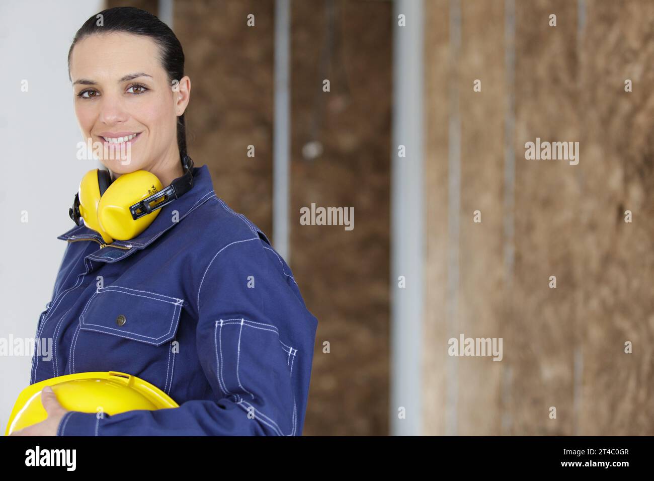 female construction worker wearing yellow helmet and protective headphones Stock Photo - Alamy