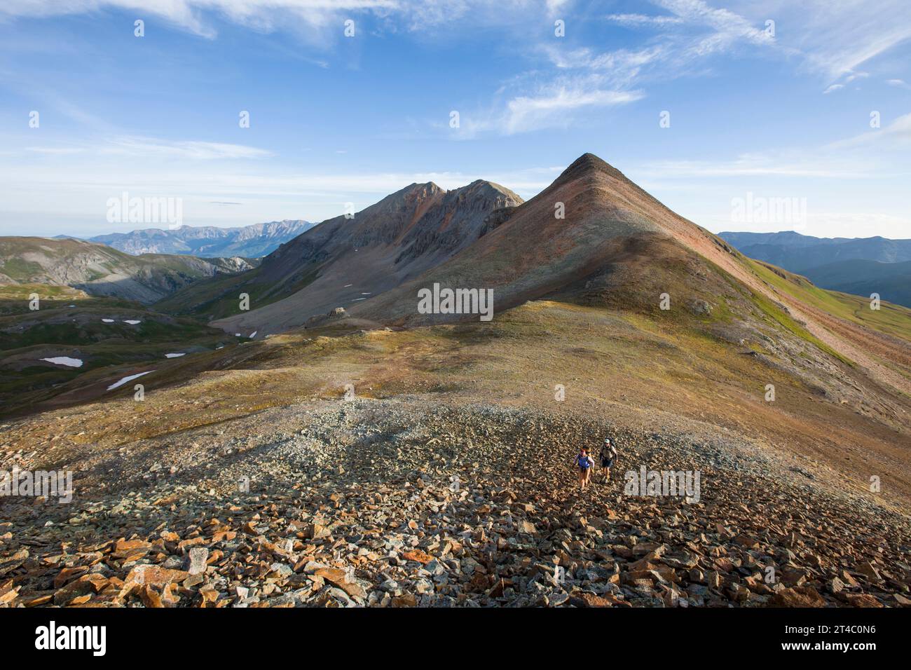 Two people hiking on slopes above tree line in the mountains Stock ...
