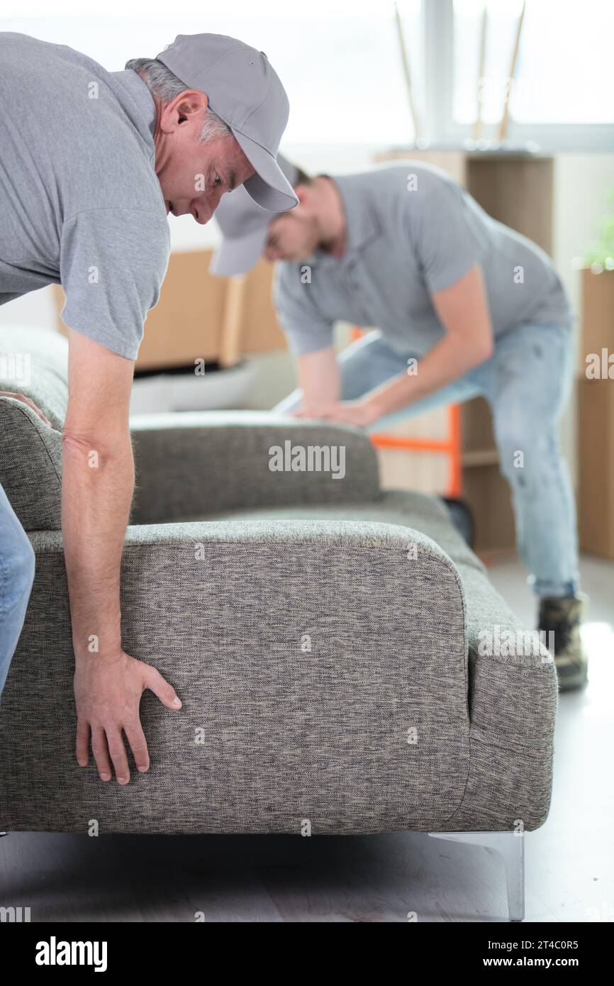 delivery men carry sofa for moving to an apartment Stock Photo - Alamy