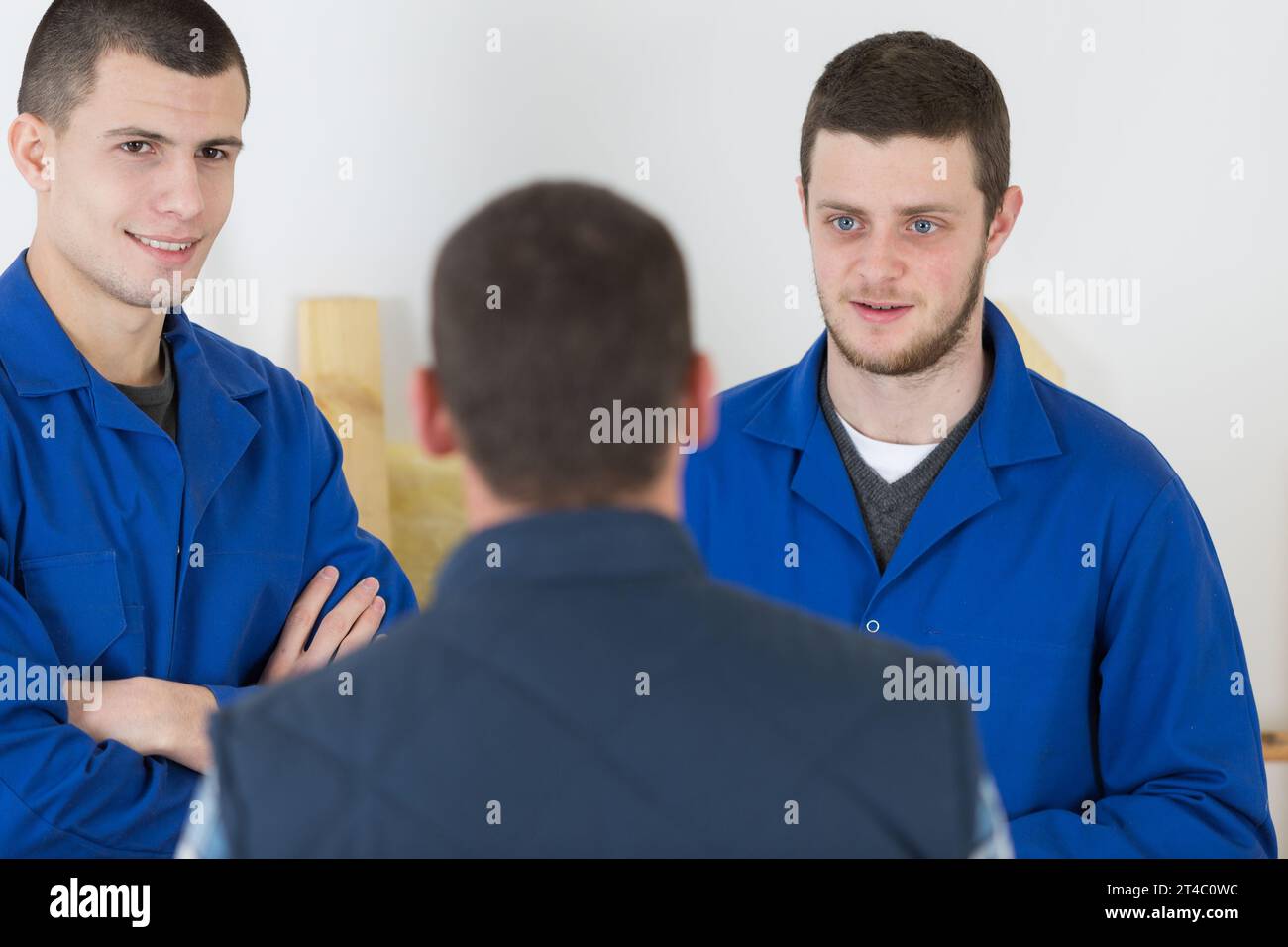 teacher talking to two young male students wearing blue jackets Stock ...