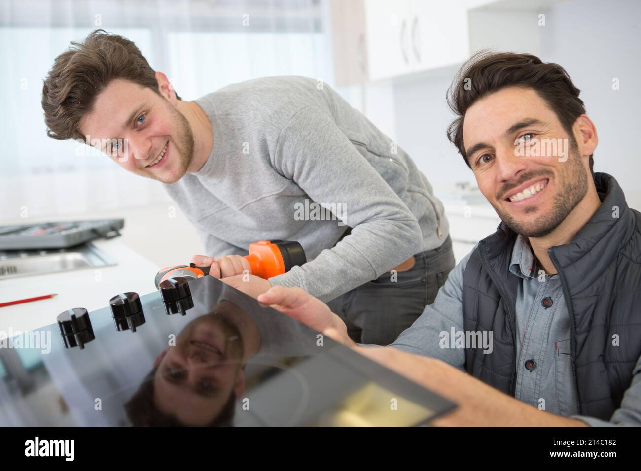 portrait of two men fitting an electric hob Stock Photo - Alamy
