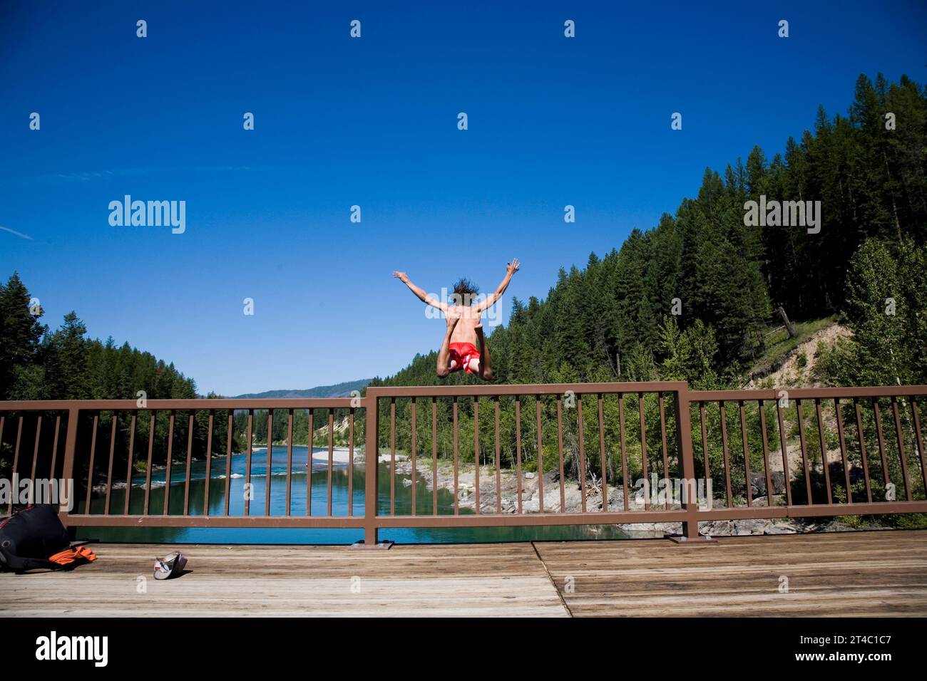 A young man leaps off a bridge over the Middle Fork of the Flathead ...