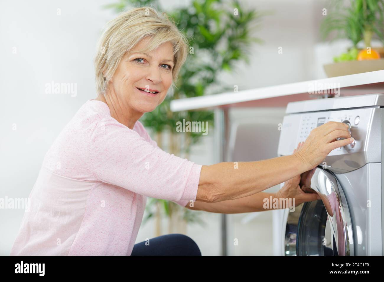 senior woman loading washing machine at home Stock Photo - Alamy