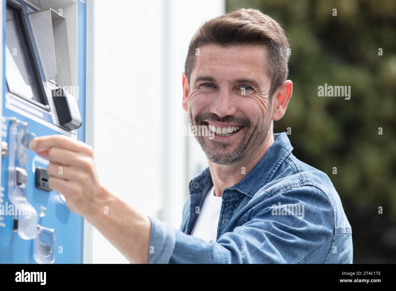 adult man putting money in a downtown parking meter Stock Photo - Alamy
