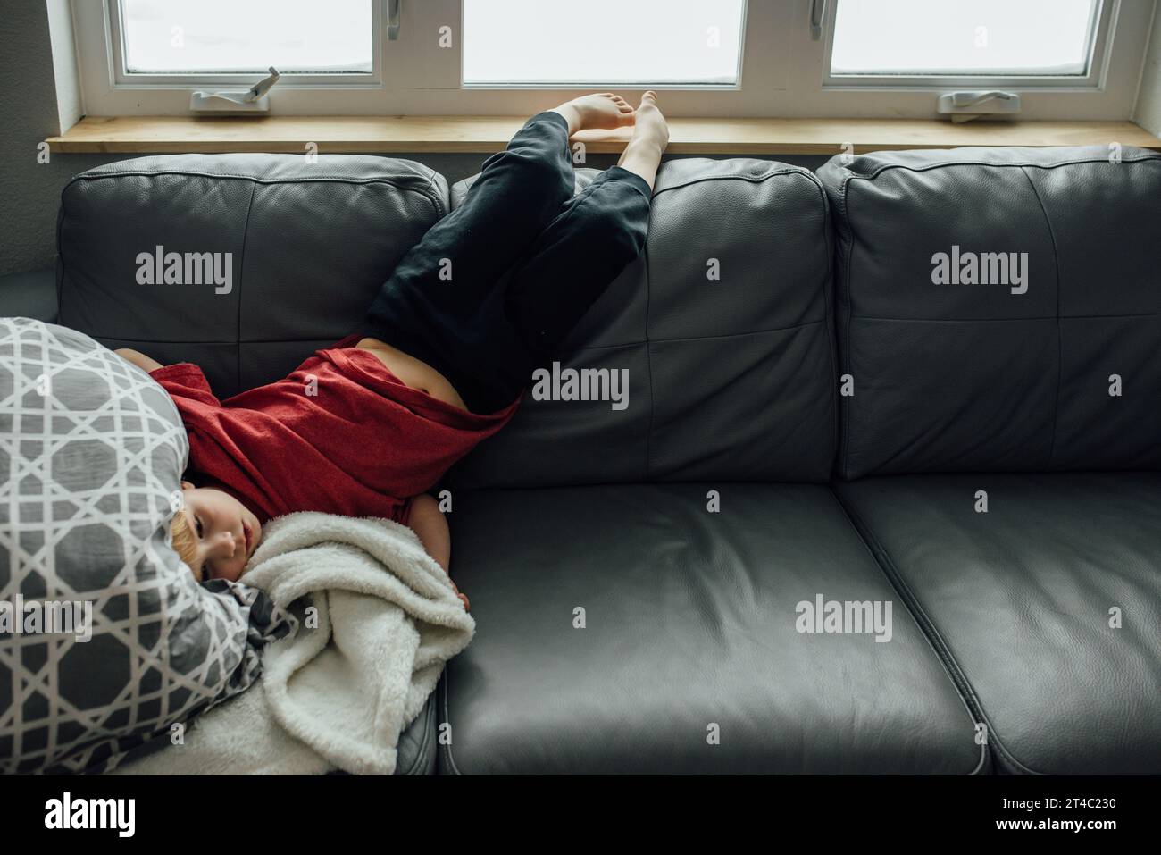 Bored young boy lays upside down over back of couch with head on Stock ...